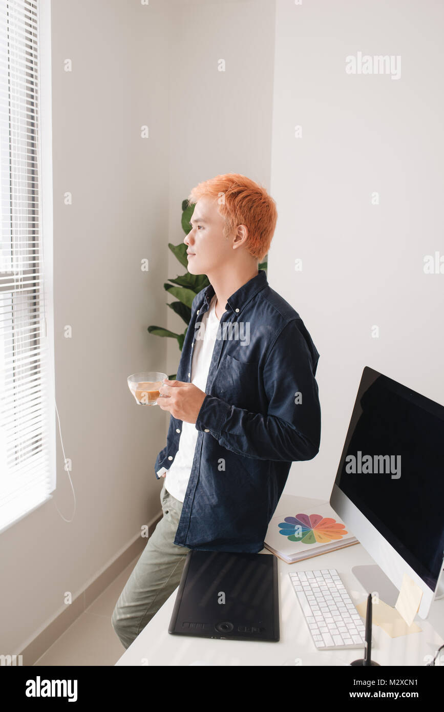 Male creative worker standing in front of desk in the creative office ...