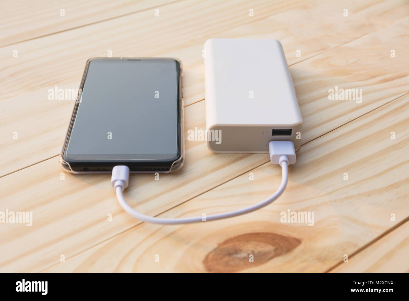 Mobile smart phones charging with power bank on desk Stock Photo - Alamy