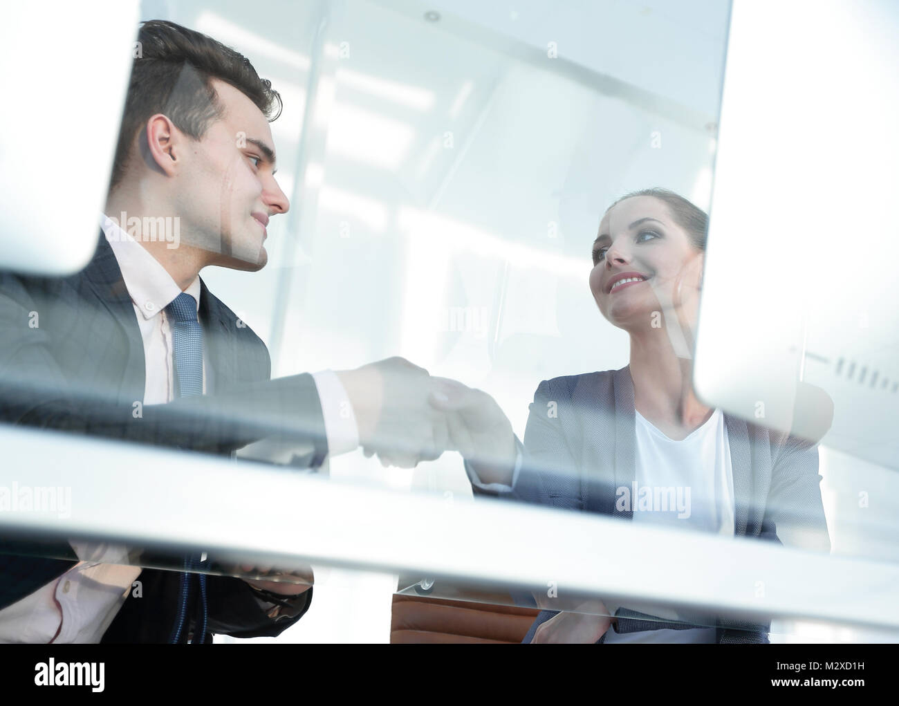 from behind the glass. handshake business partners Stock Photo - Alamy