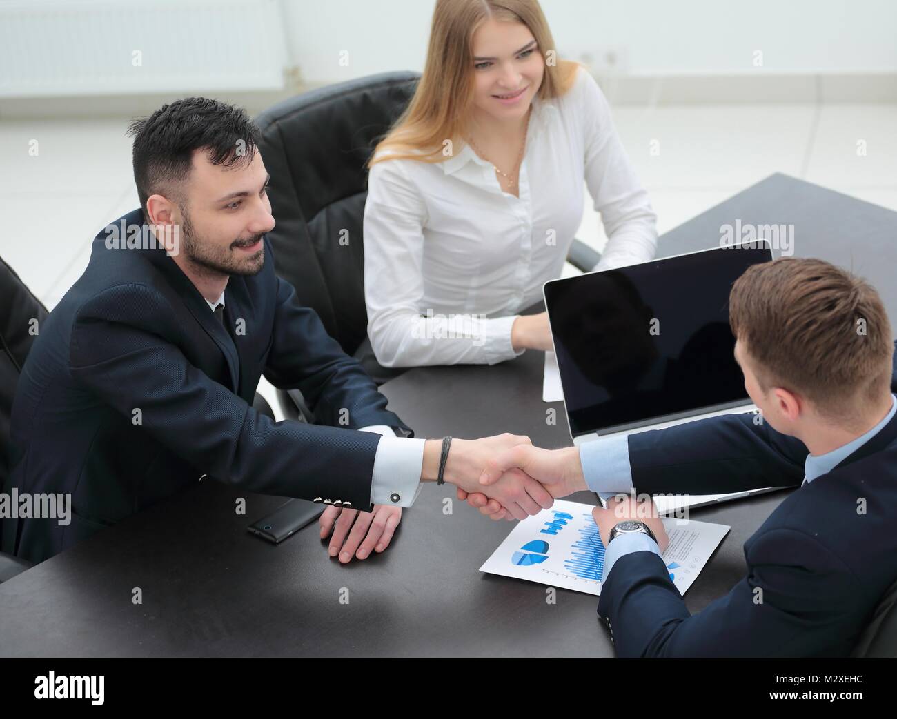 handshake financial partners sitting at the table Stock Photo - Alamy
