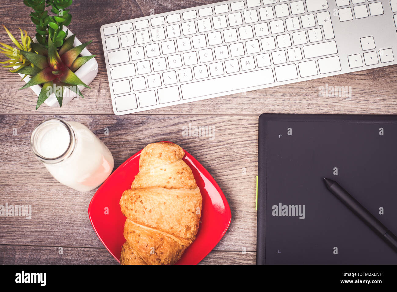 Breakfast on the desk. Working table with keyboard, graphic tablets ...