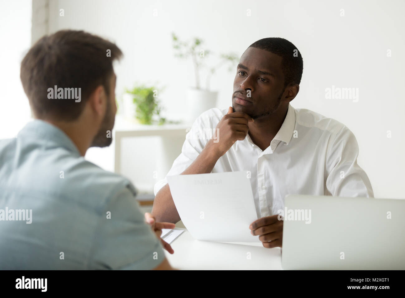 Serious attentive african hr manager listening to caucasian candidate ...