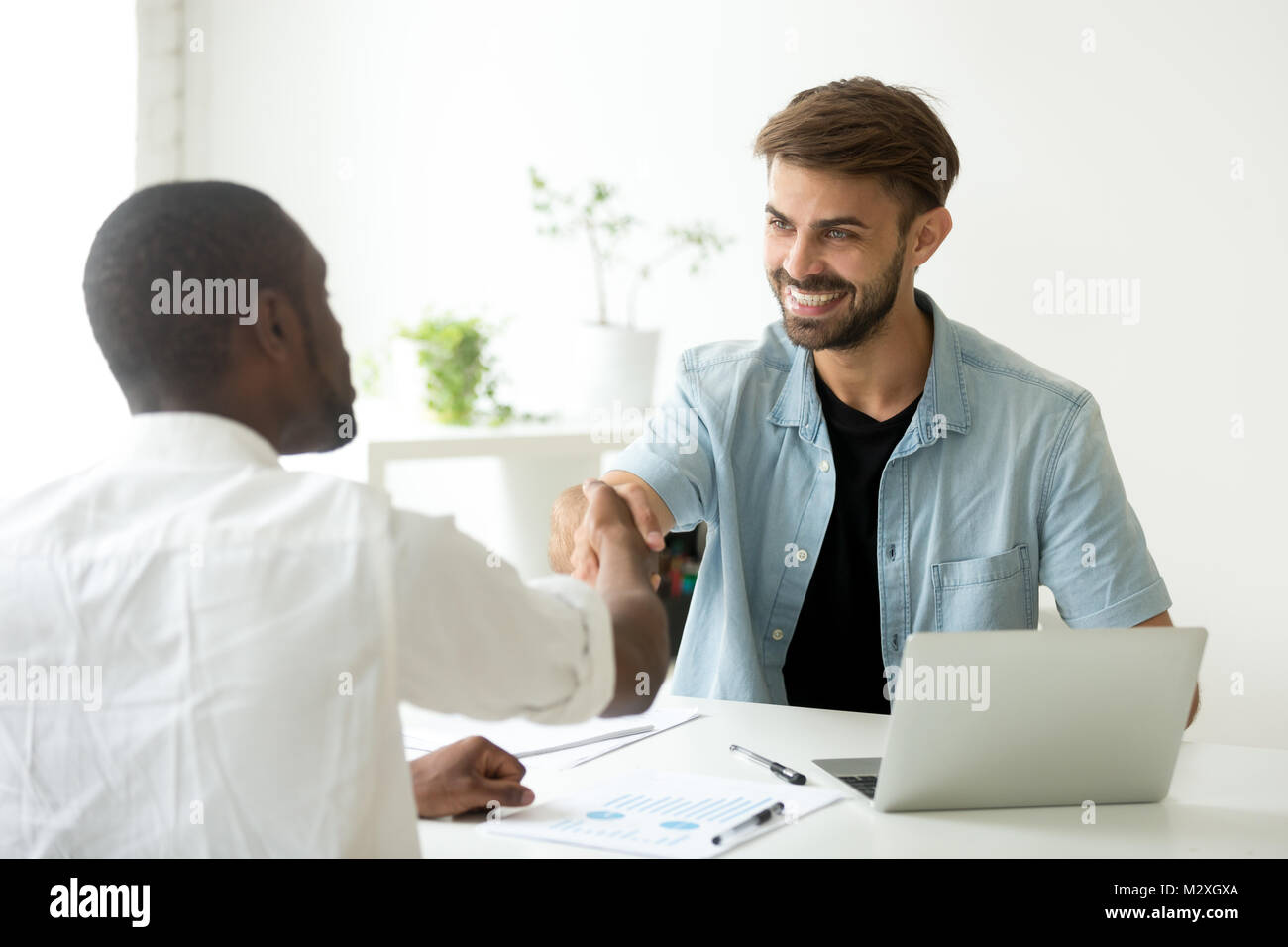 Smiling caucasian manager and african client shake hands making Stock ...