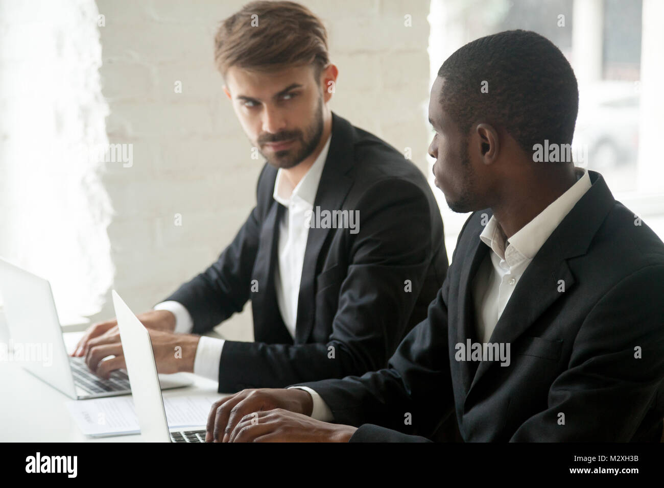 Caucasian businessman looking at african business rival, rivalry Stock ...