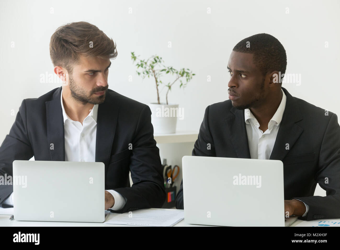 Multiracial office rivals looking at each other, rivalry at work Stock ...