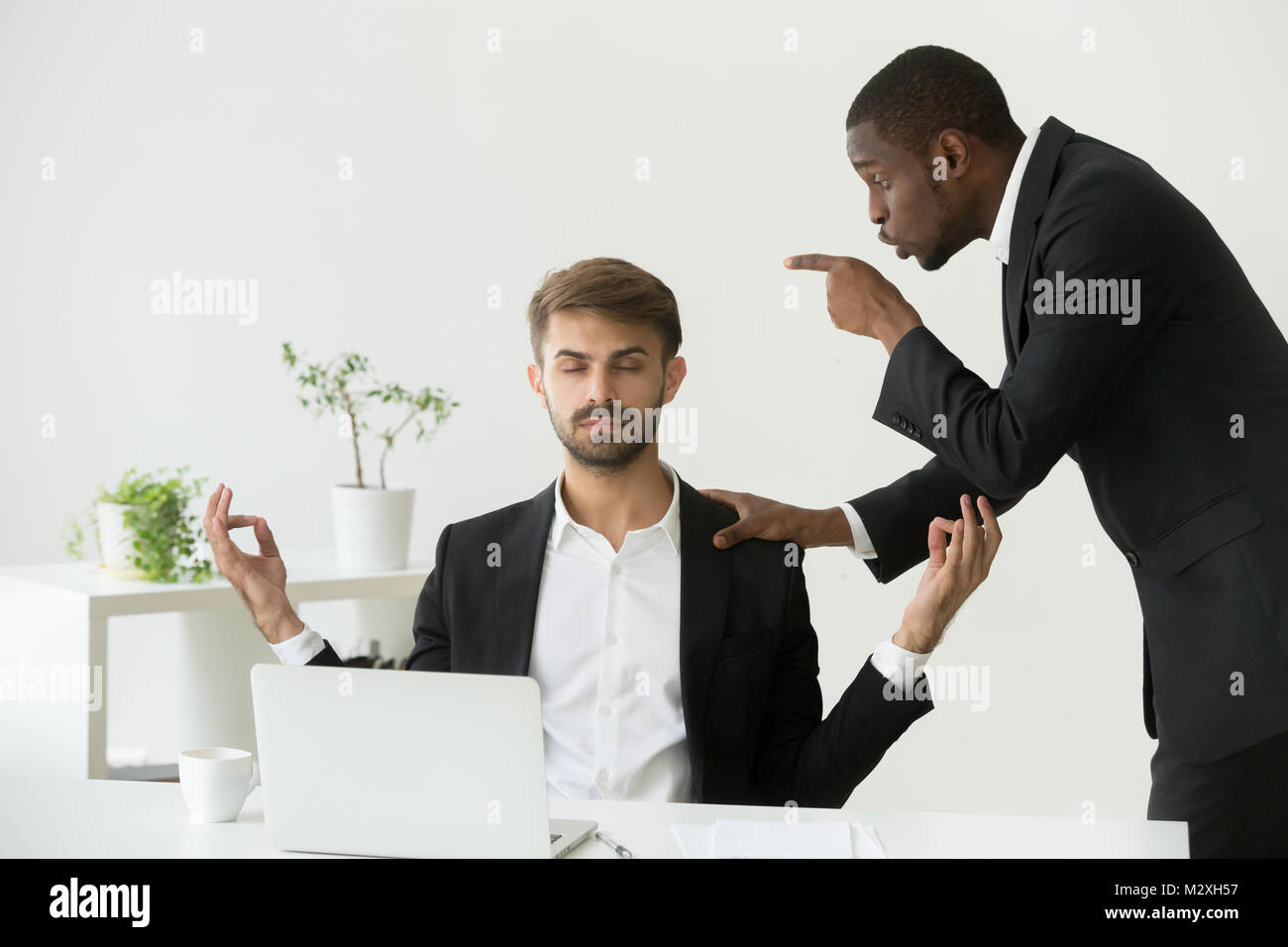 Caucasian employee meditating at workplace ignoring angry boss s Stock ...