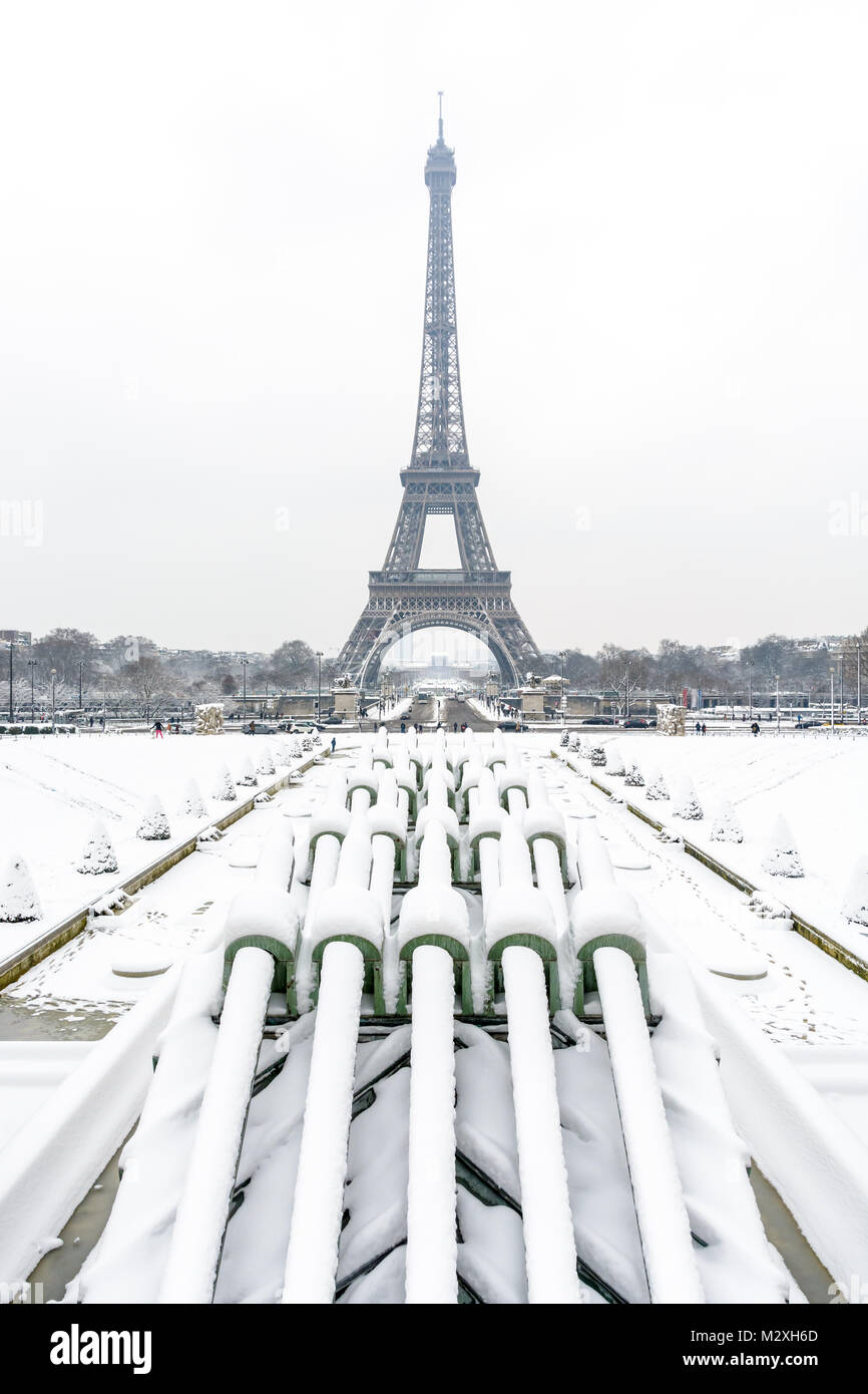 Winter in Paris in the snow. The Eiffel tower with the water cannons of ...
