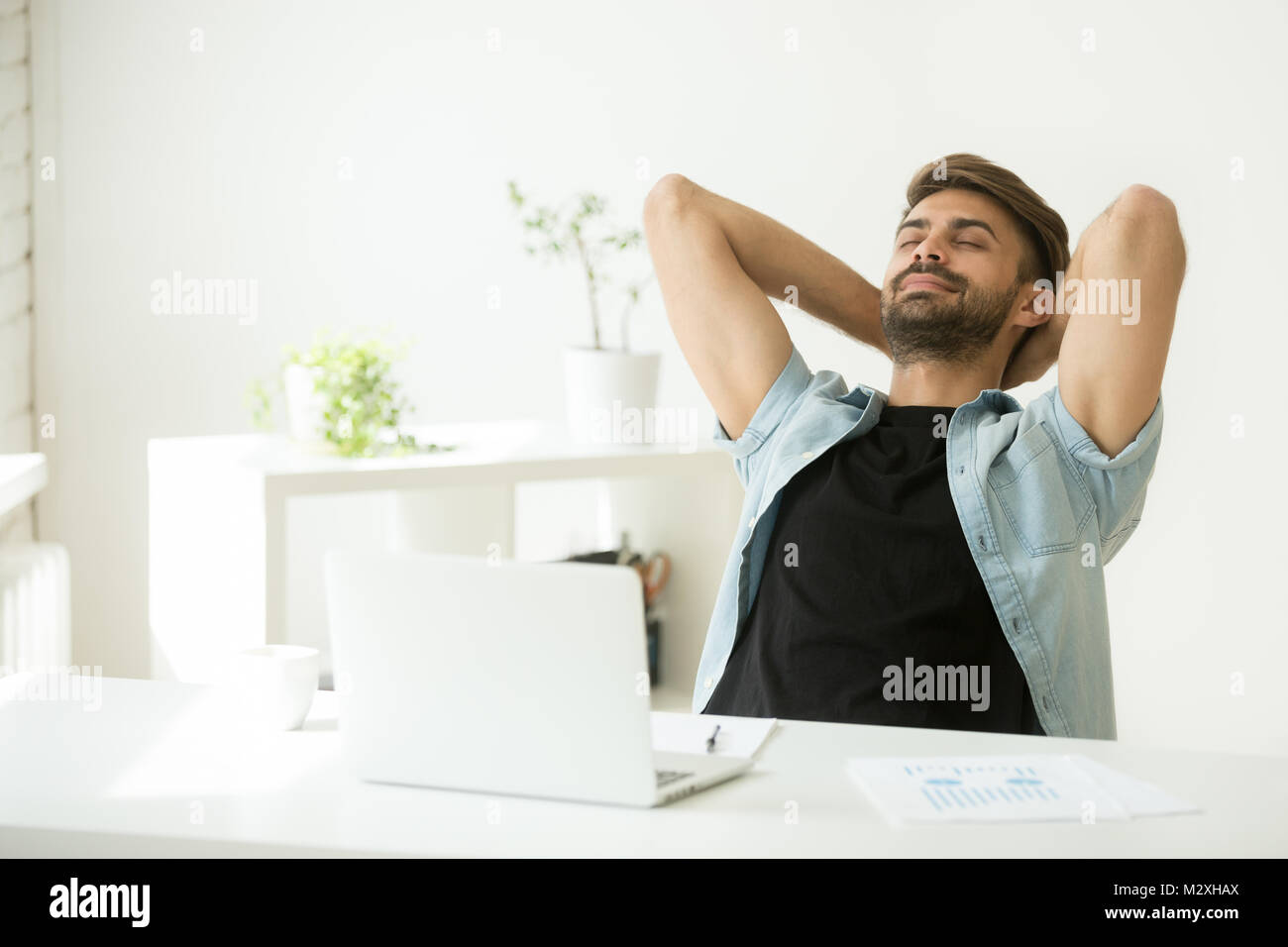 Relaxed man resting from work on laptop hand behind head Stock Photo ...