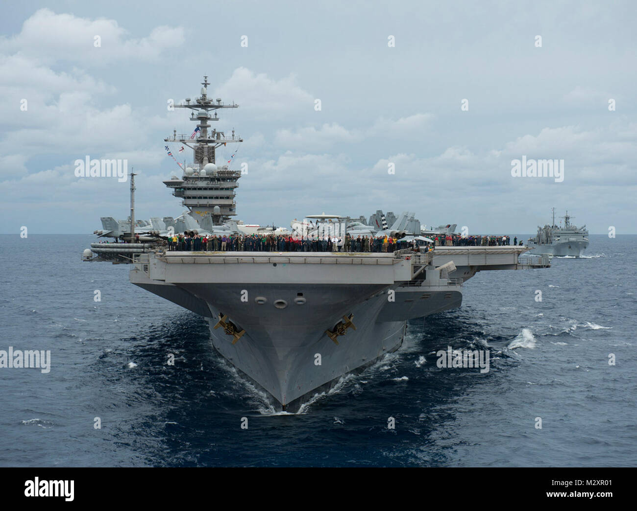 Sailors gather on the flight deck as Nimitz-class aircraft carrier USS ...