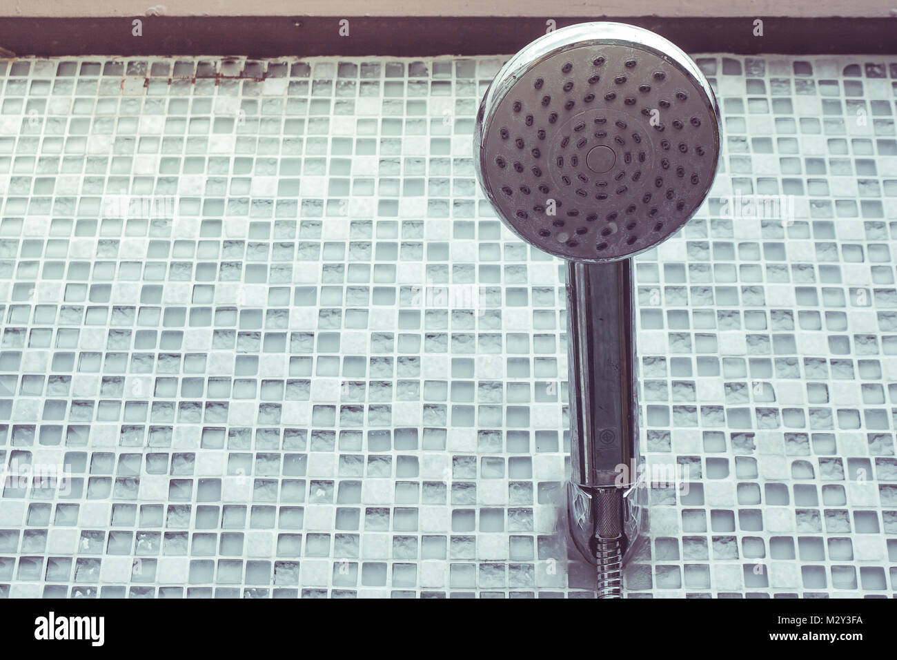 Close up old silver shower head with green mosaic tiles background in ...