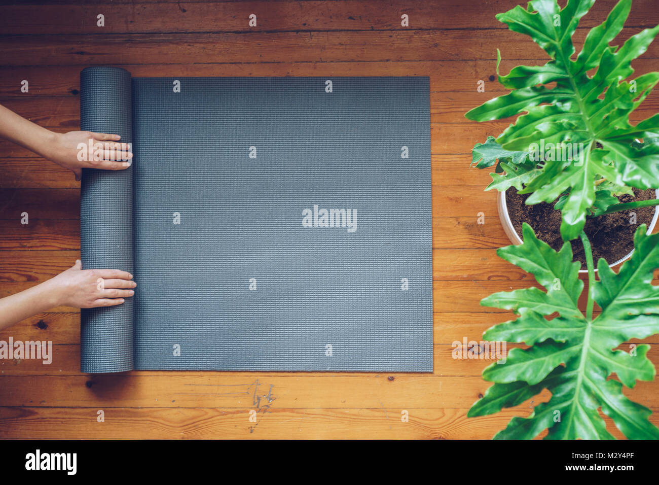 Woman rolling her mat after a yoga class, top view Stock Photo - Alamy