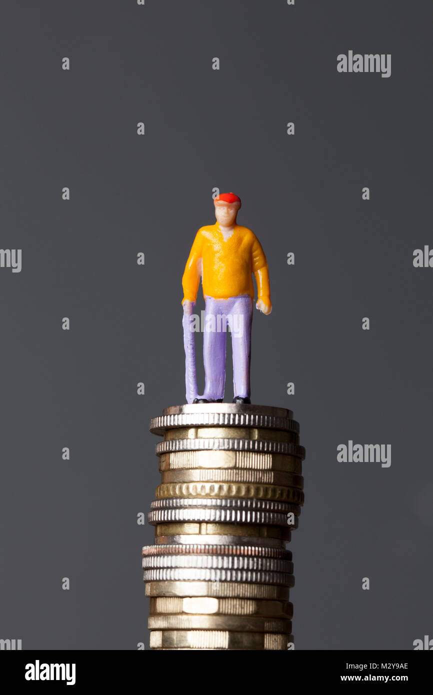 Pension concept. Old person figure on a stack of coins Stock Photo - Alamy