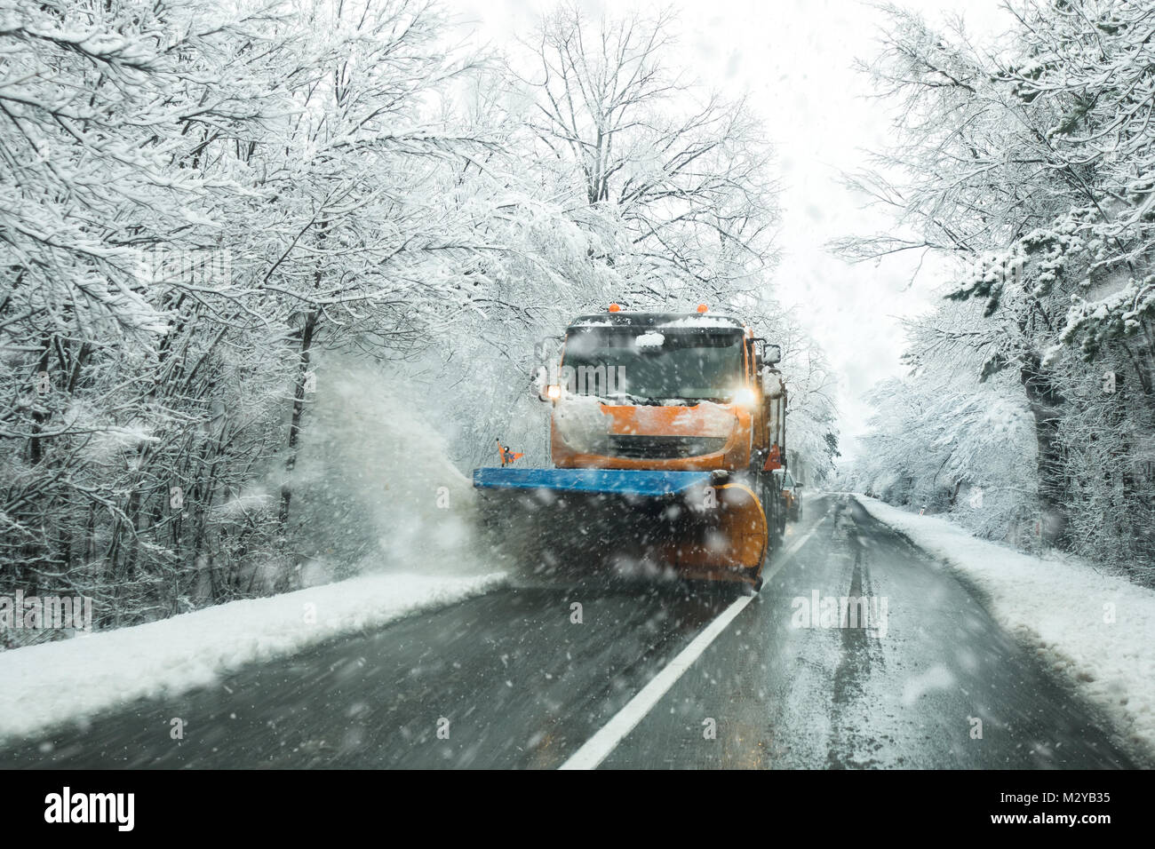 Front view of snowplow service truck and gritter spreading salt on the ...