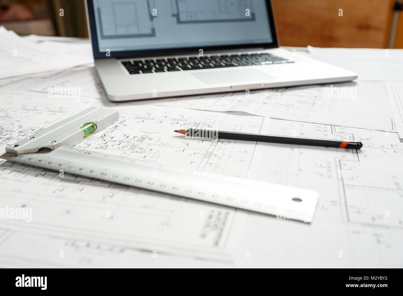 Image of laptop, pencil, calculator and a level ruler standing on top ...