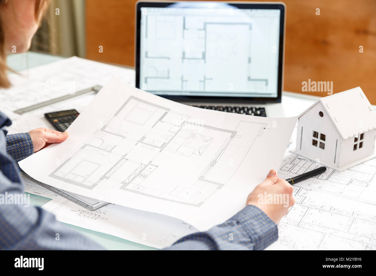 Young female architect and designer working on blueprint project of new ...