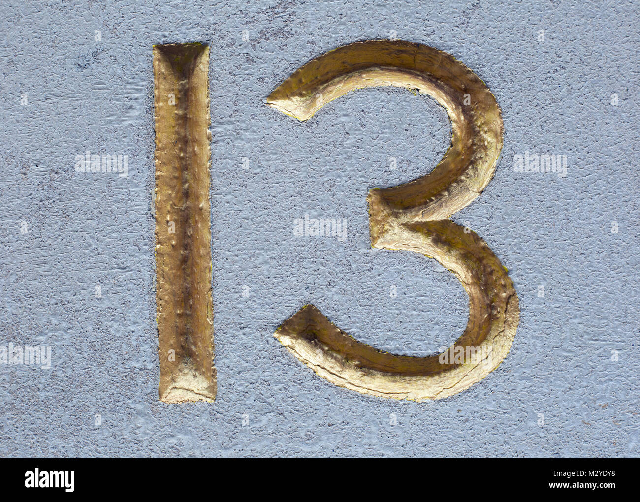 Number 13 in bevelled gold gilded numerals chased into light stone ...