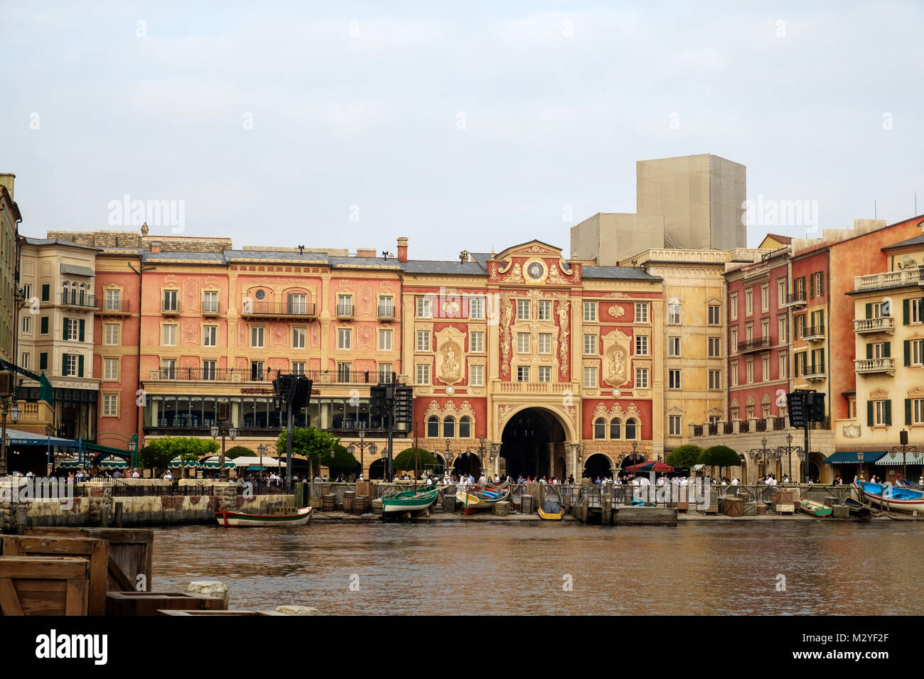 Seafront view of Italian style Harbor. Boats docked. Row of pale yellow ...