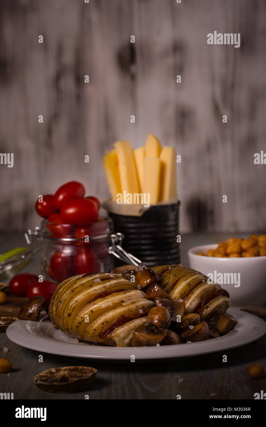 Vertical photo with two roasted whole potatoes. Vegetable is sliced and ...