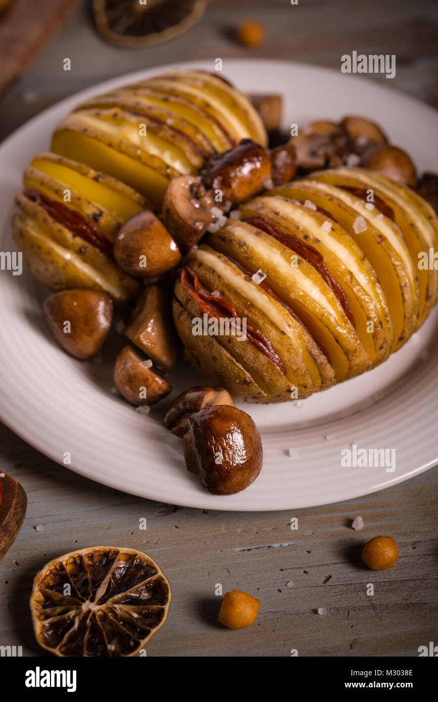 Vertical photo with two roasted whole potatoes. Vegetable is sliced and ...