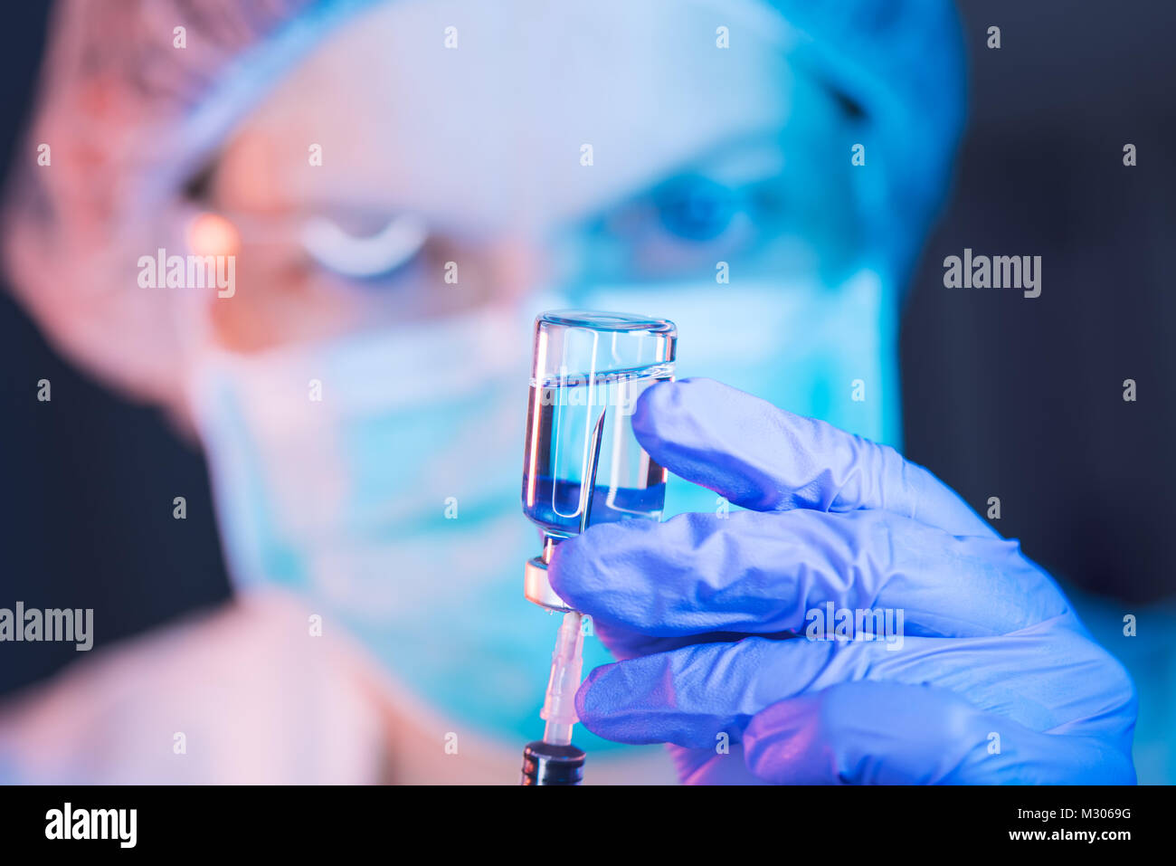 Doctor drawing up solution from vaccine bottle and filling syringe ...