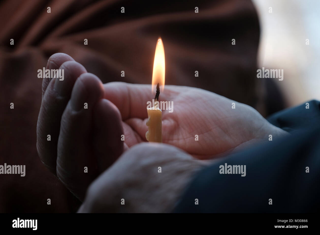 A man holding a burning candle Stock Photo - Alamy