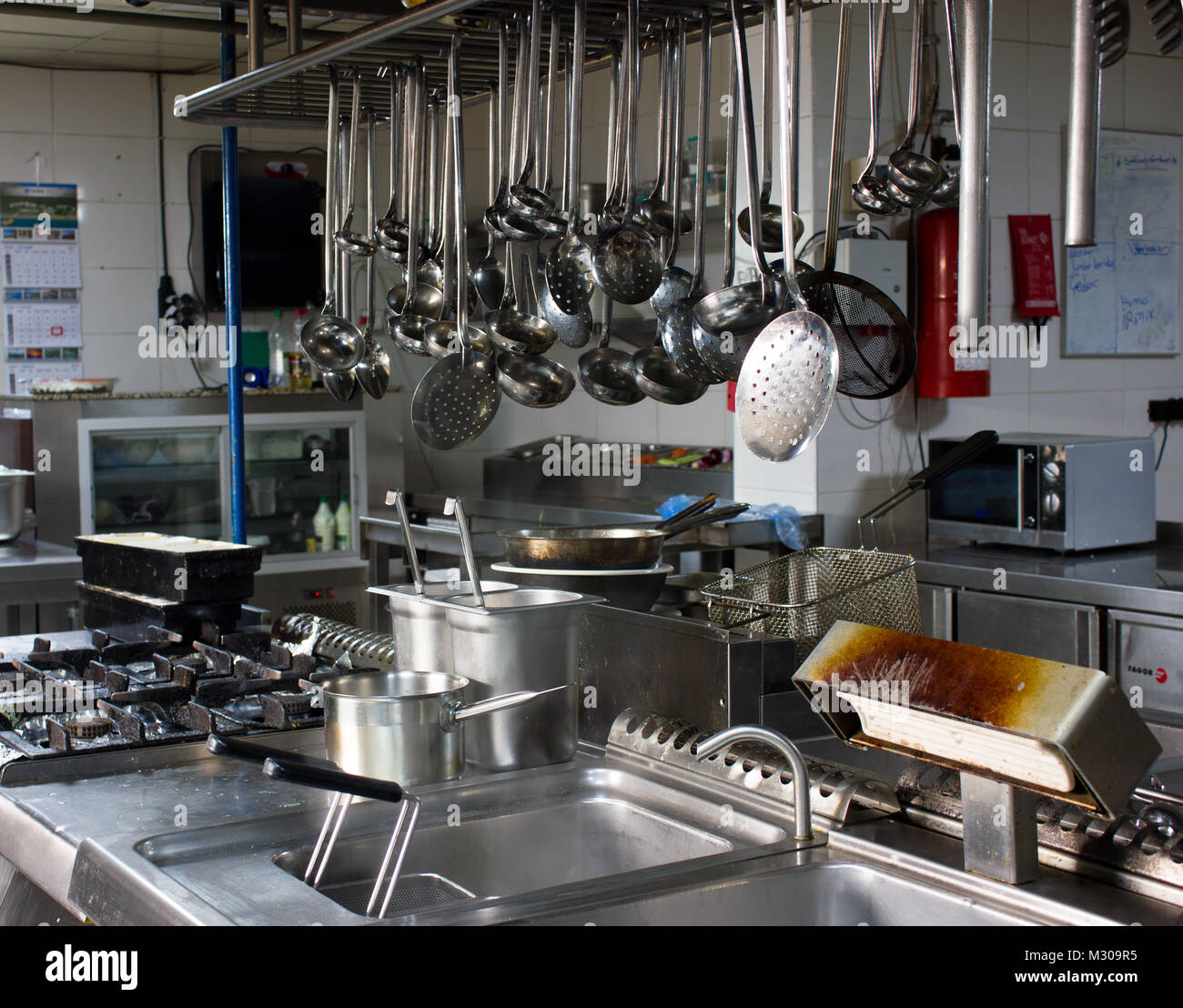 Professional cuisine in restaurant. Steel blades, tongs, scoops and ...