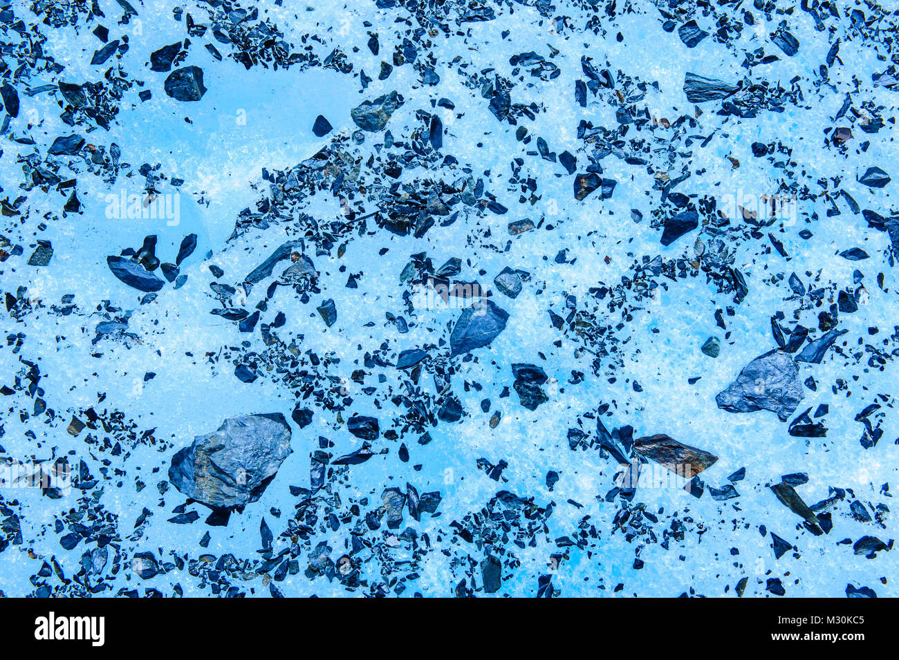 Stones frozen in the blue ice of Fox Glacier, South Island, New Zealand ...