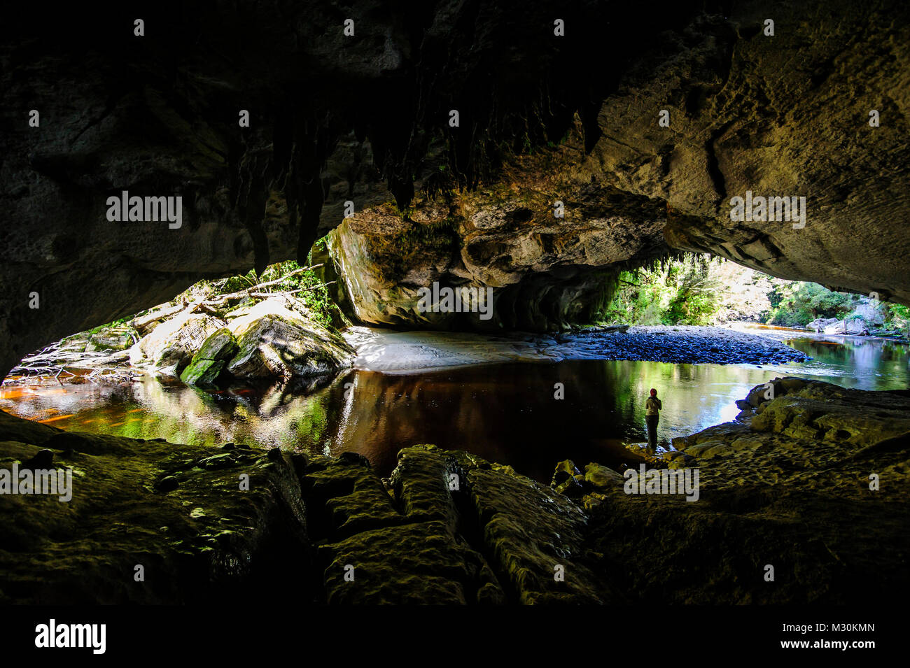 Woman enjoying the stunning Moria gate arch in the Oparara Basin ...