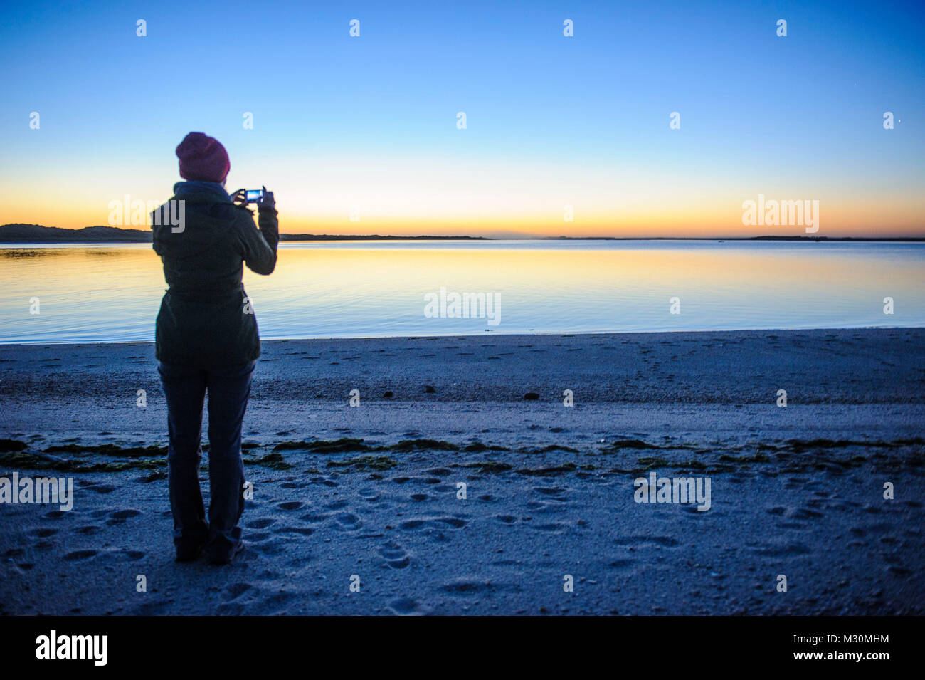 Woman photographing the stunning light over the flat ocean hi-res stock ...