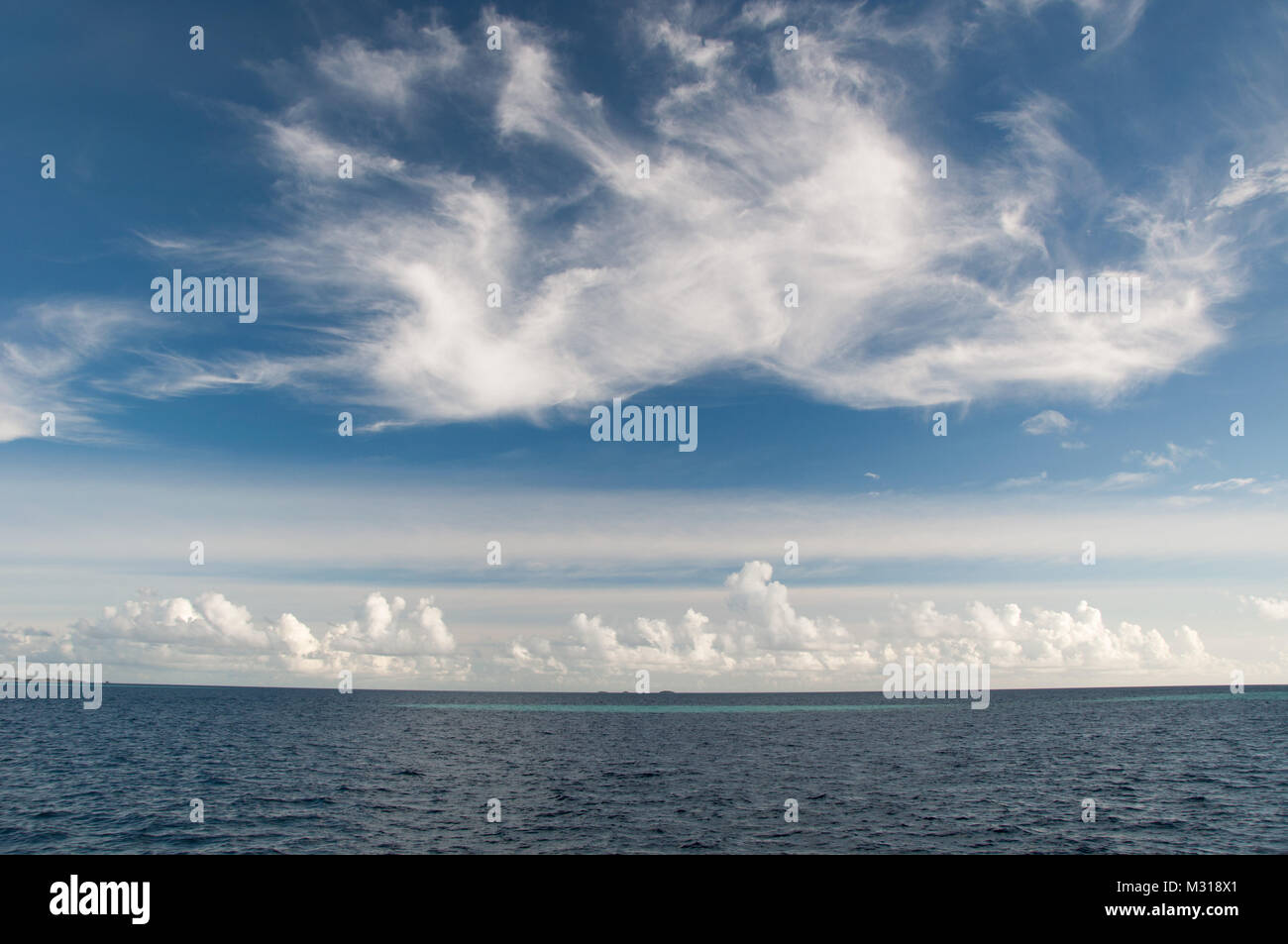 Waters of the Indian Ocean with a blue crescent of a coral reef, under ...