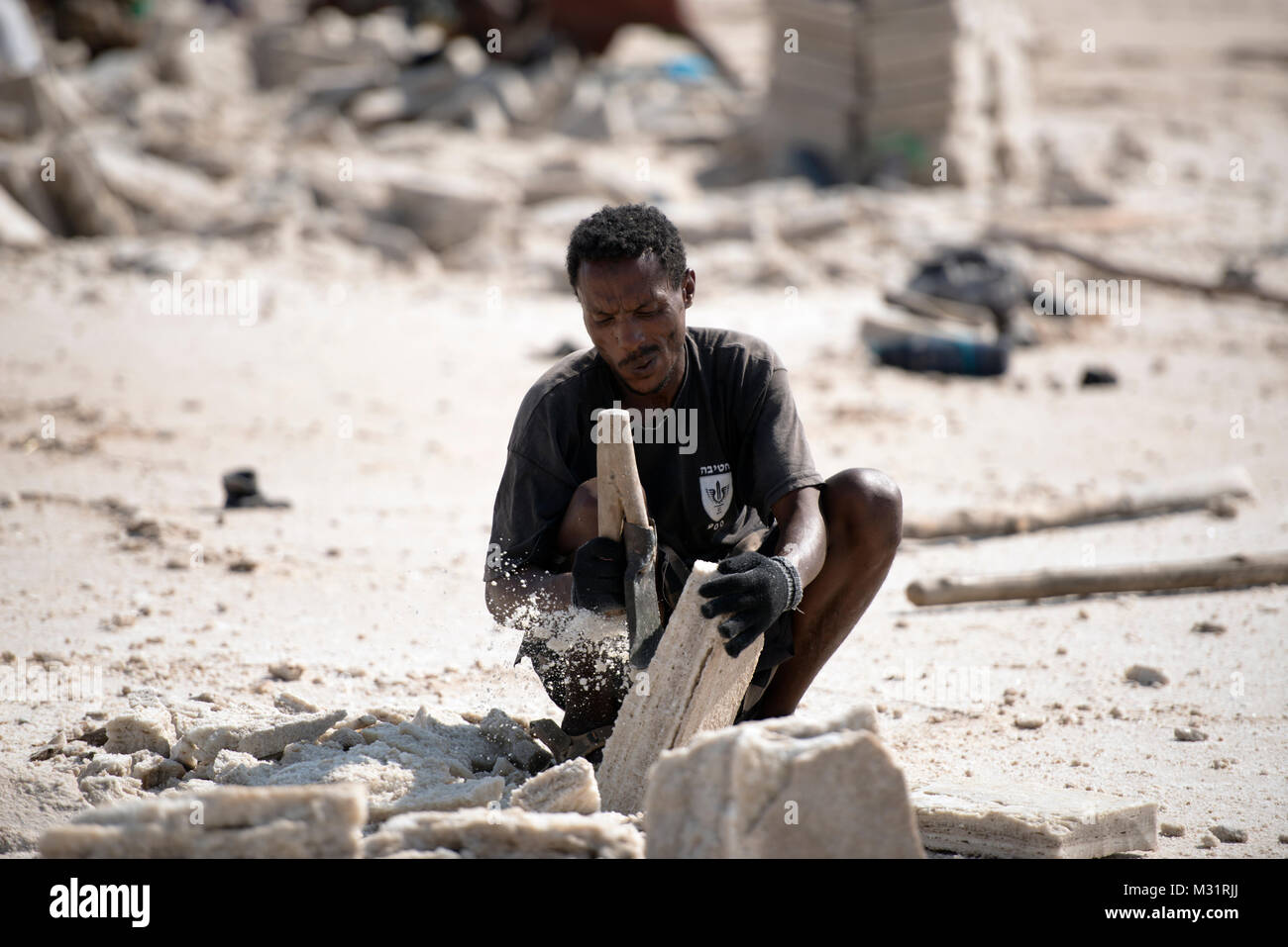 An Afar salt miner chops a block of salt before it is taken to be sold ...