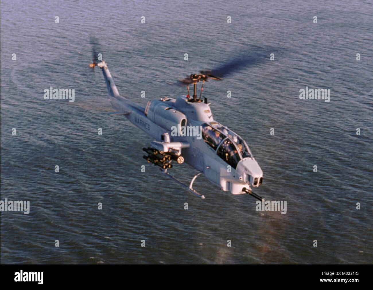 an AH-1W flies over the ocean at low-level armed with TOW missiles and ...