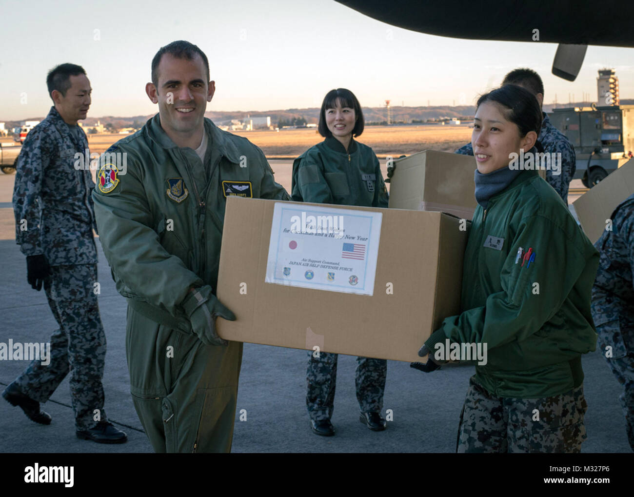 A Japanese and U.S. Airman carry a box of donated goods provided by the ...