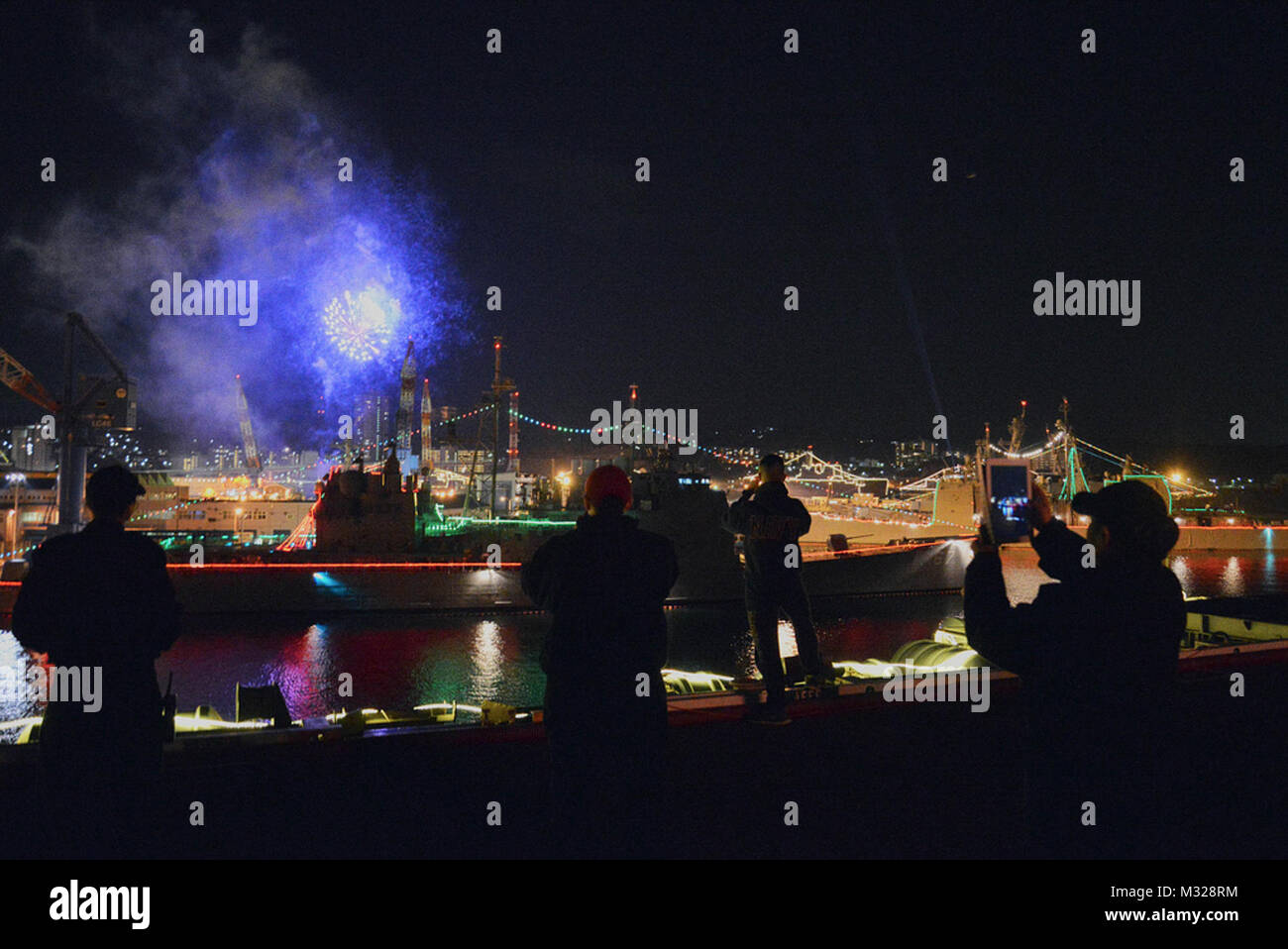 Sailors watch a New Year's Eve fireworks show from the flight deck of ...