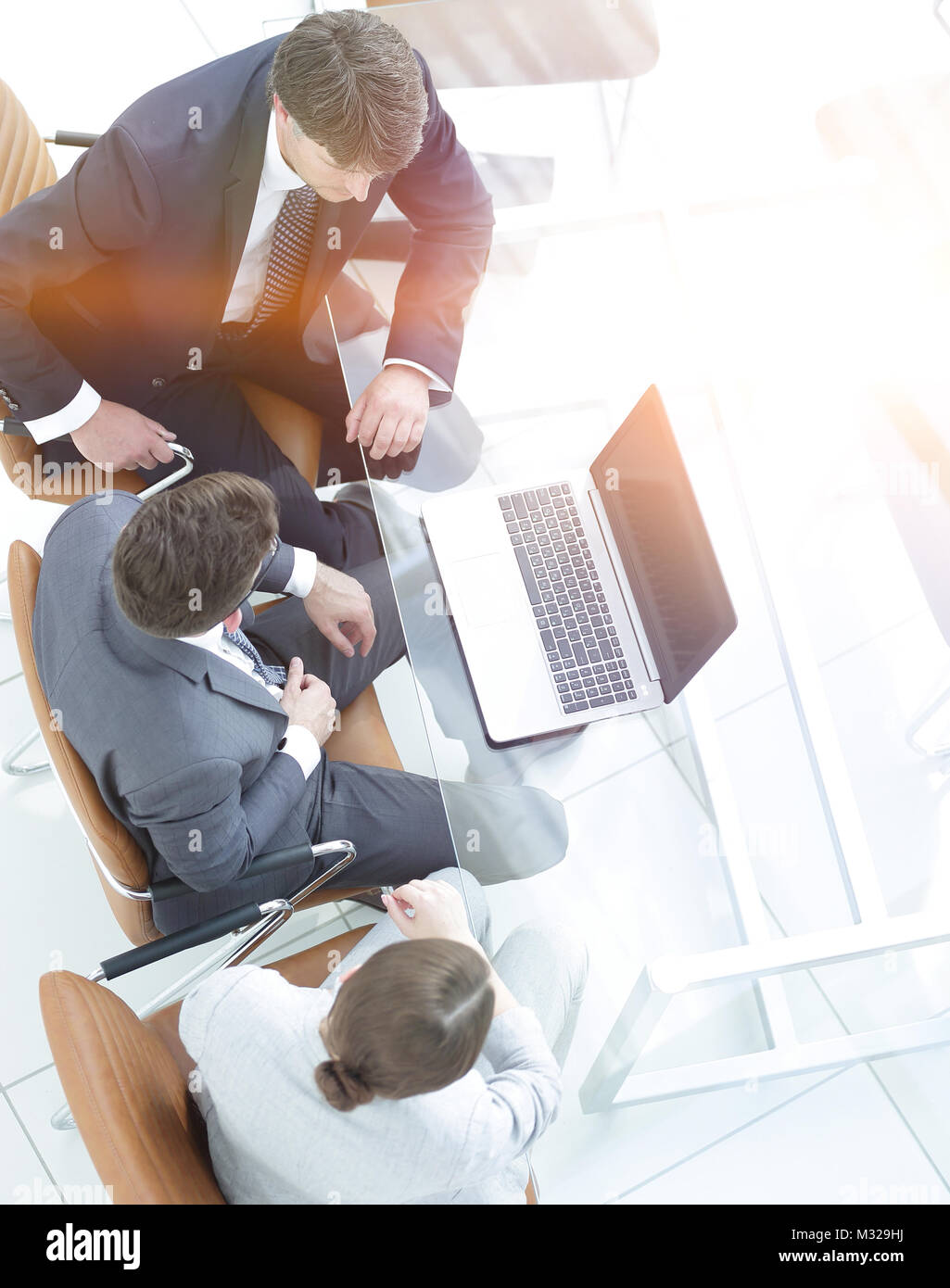 Three business people, meeting around a boardroom table Stock Photo - Alamy