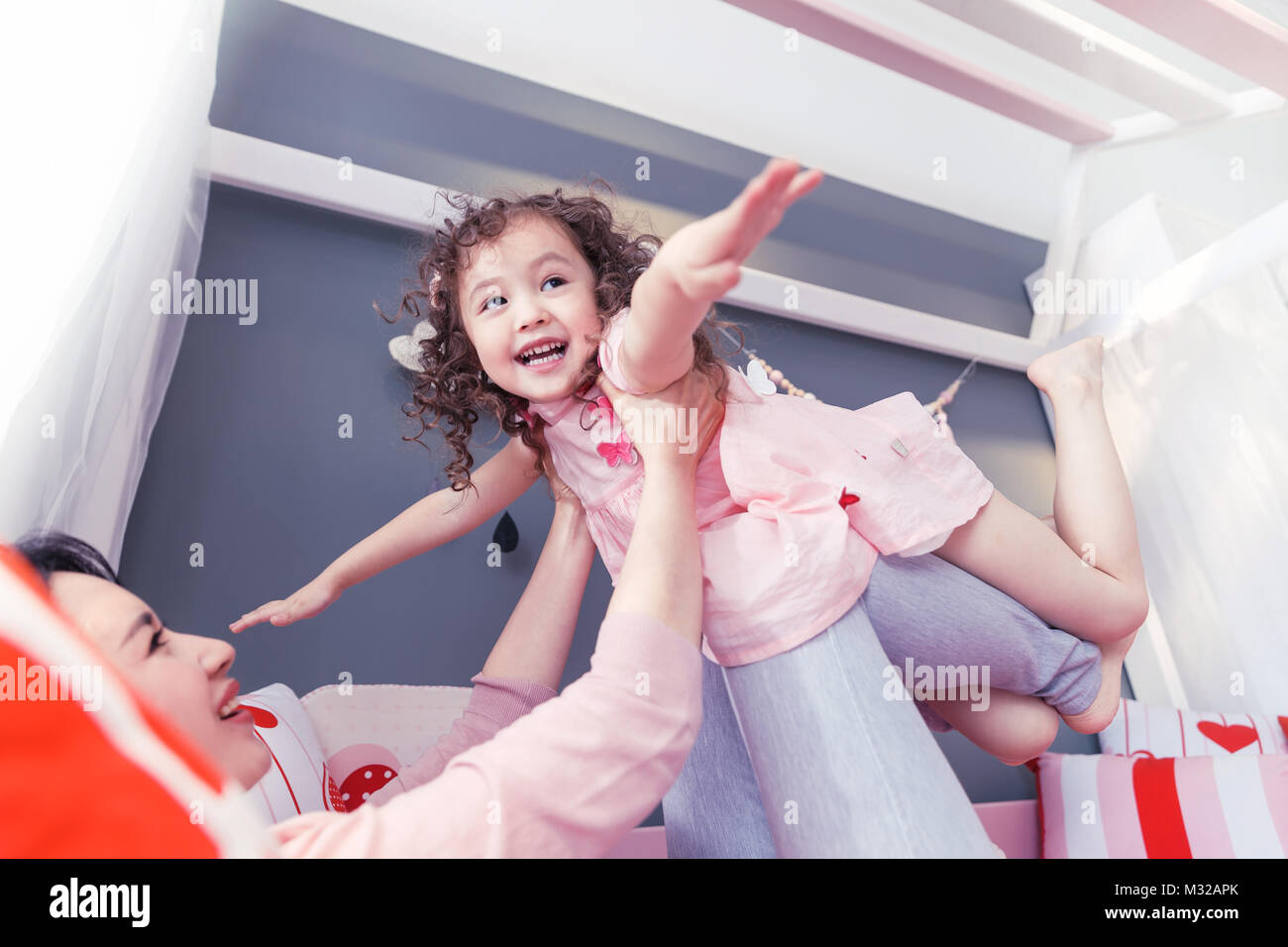 Cute little girl and her mother play in the bedroom Stock Photo - Alamy