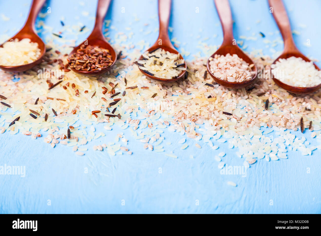 Five spoons with different grades of rice on an old wooden background ...