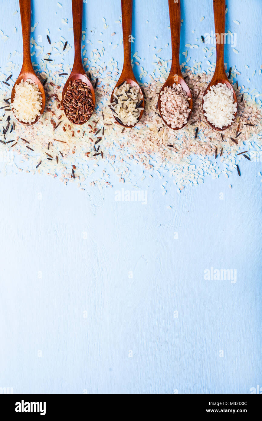 Five spoons with different grades of rice on an old wooden background ...