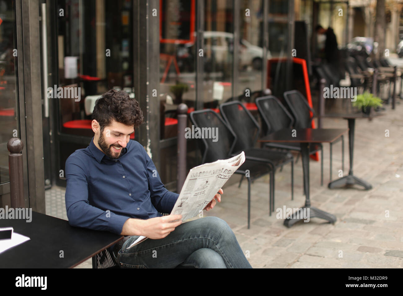 Journalist with close up face reading newspaper article at cafe Stock ...