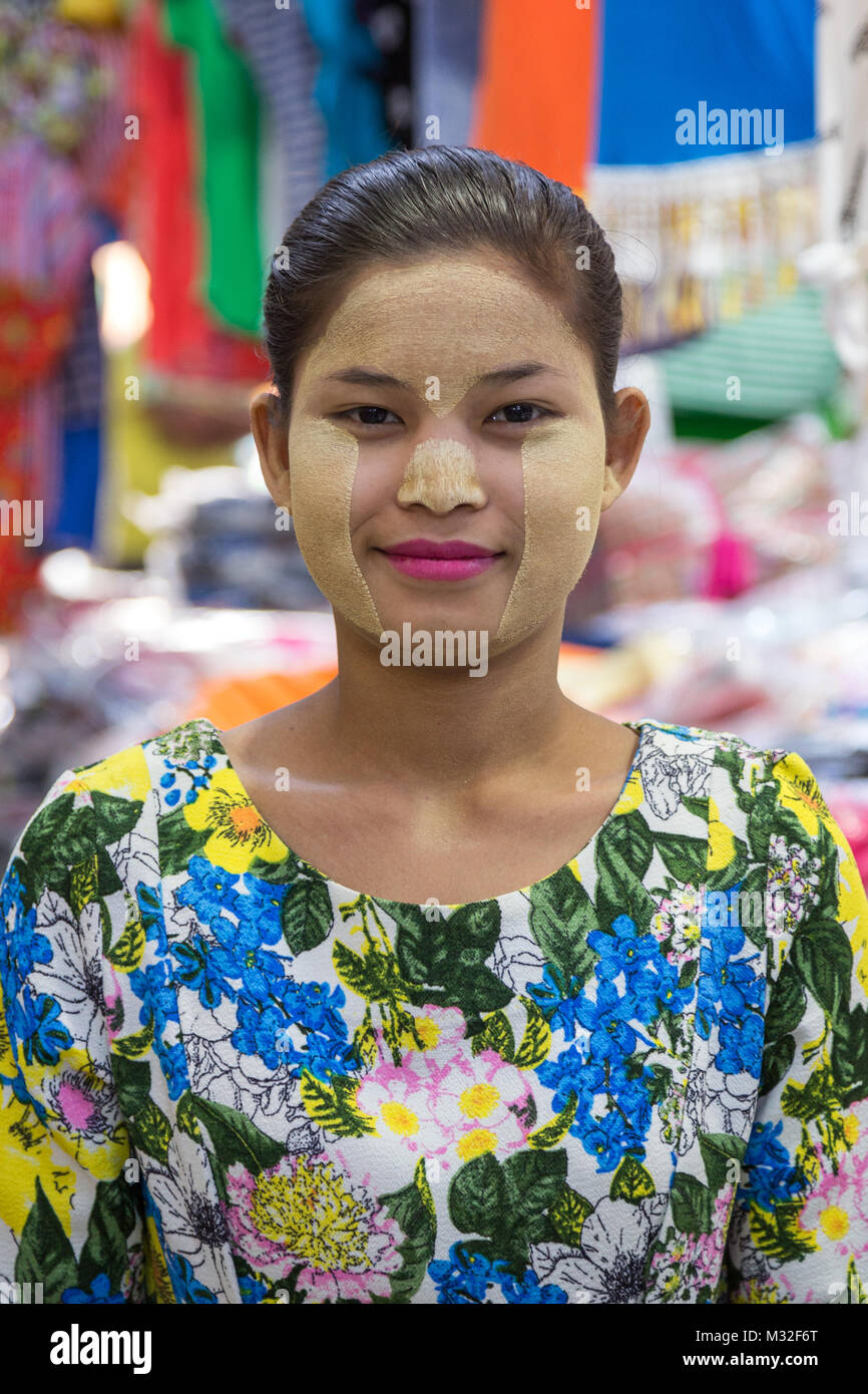 Portrait of a young happy Myanmarese saleswoman with thanaka paste on ...