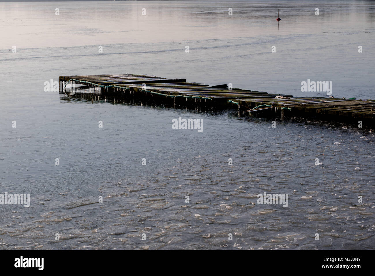 Fishing pier on a frozen lake. Bridge for mooring fishing boats and ice ...