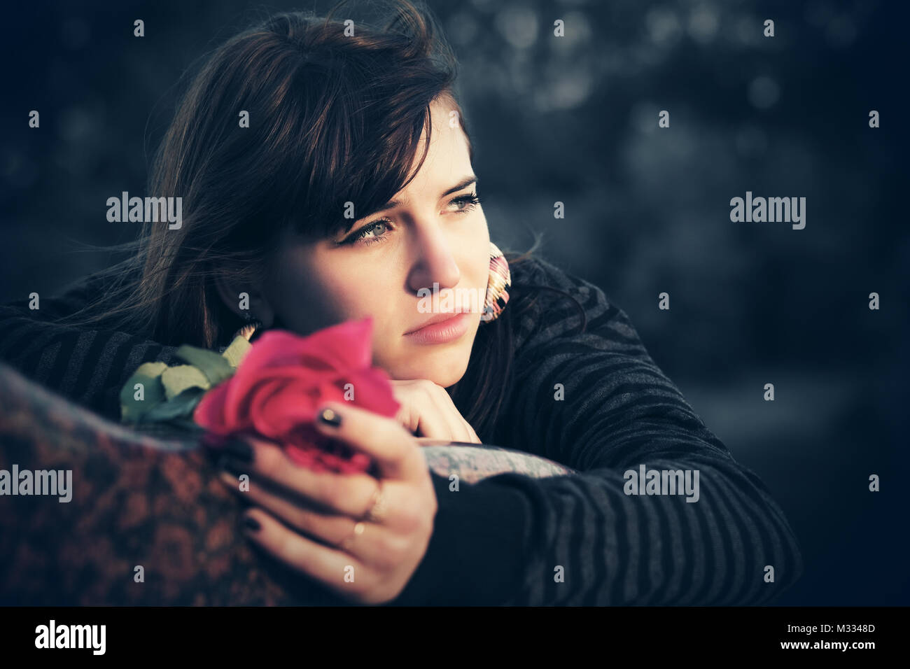Sad young woman with a red rose Stock Photo - Alamy
