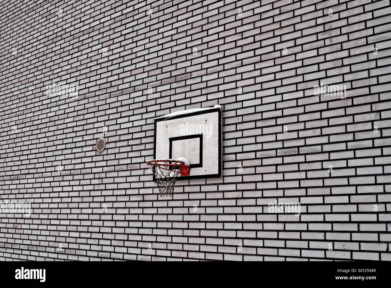 An old basketball hoop attached to a black and white brick wall in the ...