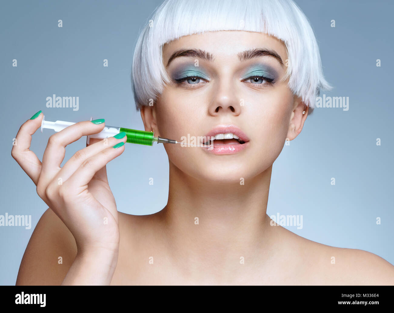 Beautiful woman face with syringe makes cosmetic injection in the lips ...