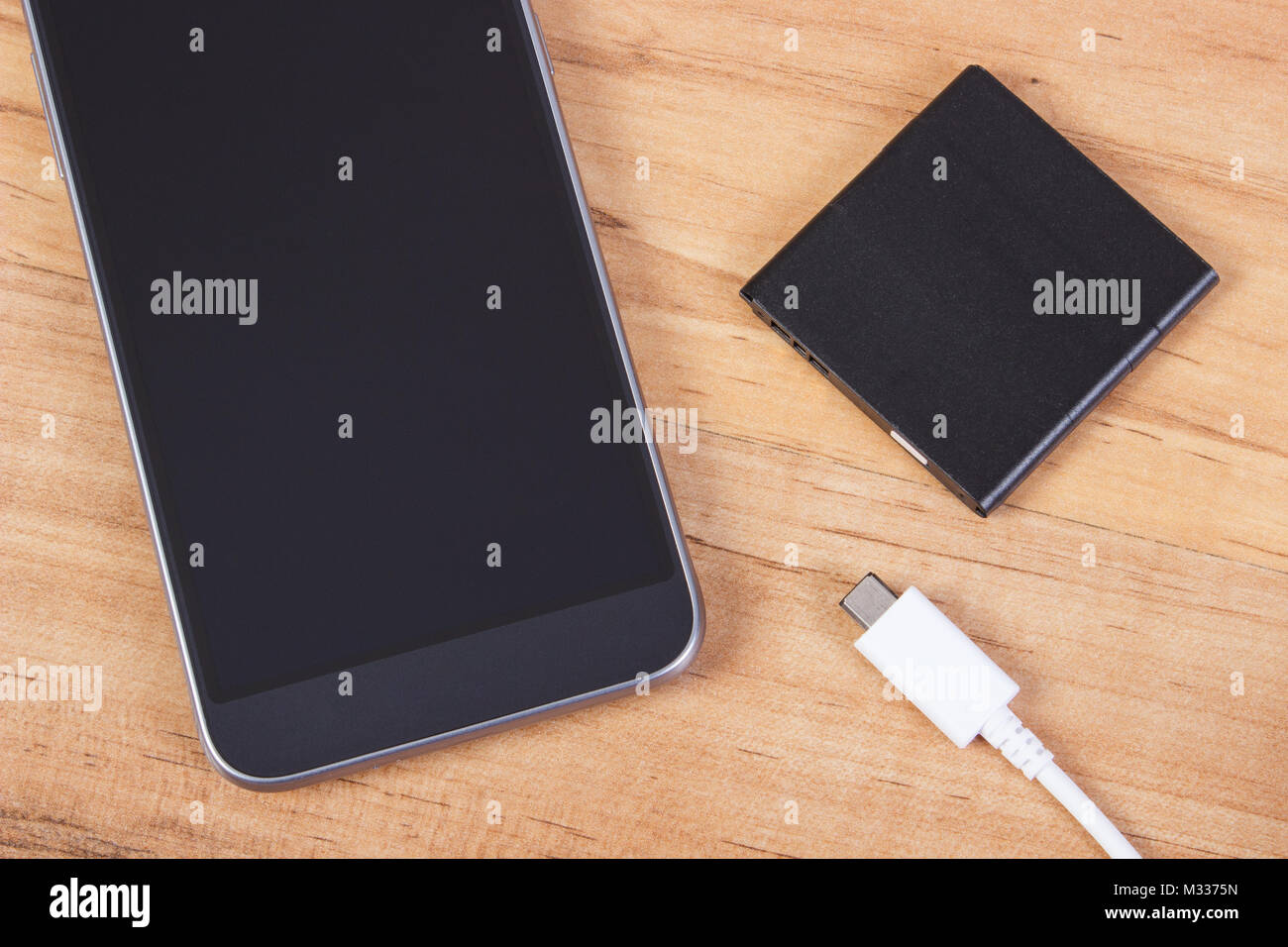 Mobile phone, plug of charger and telephone battery on table ...