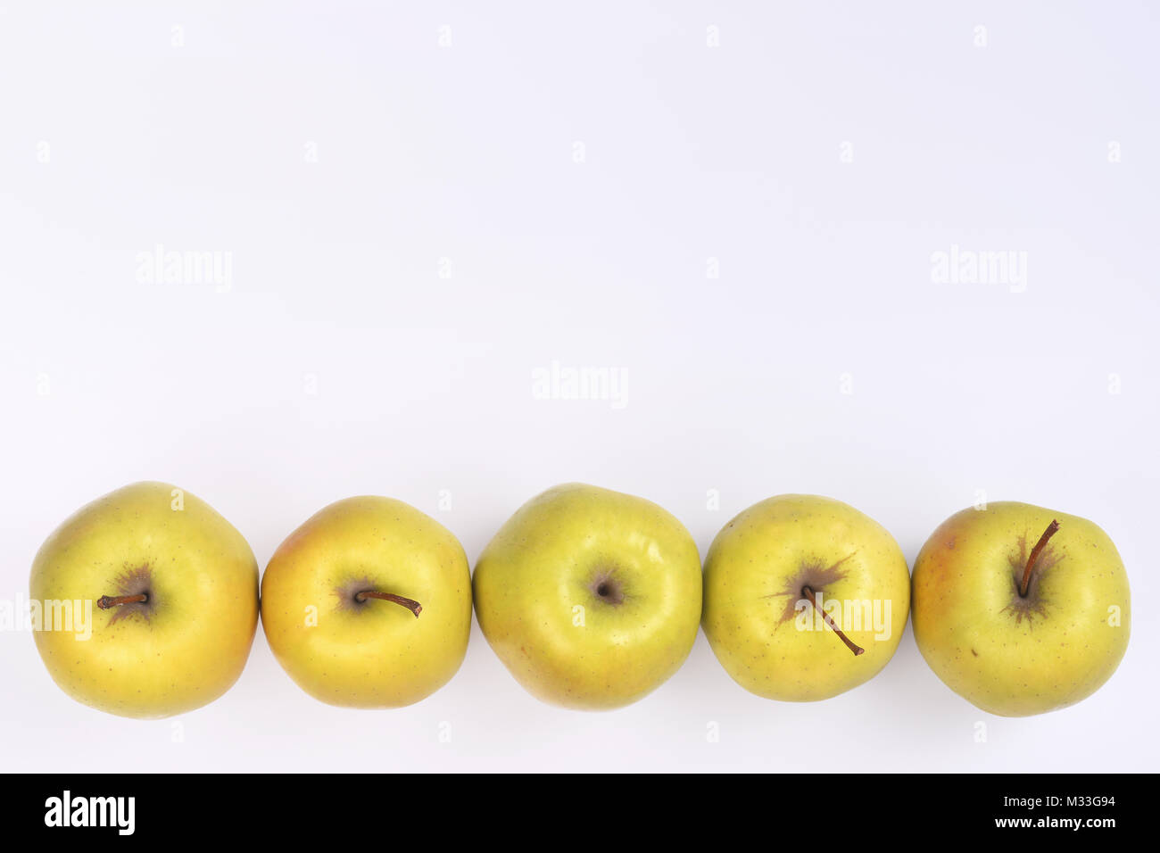 Five fresh green apples lie at the bottom of a white sheet, a top view ...