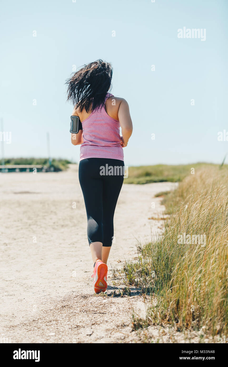 Young woman jogging cross-country running in summer seaside. Concept ...