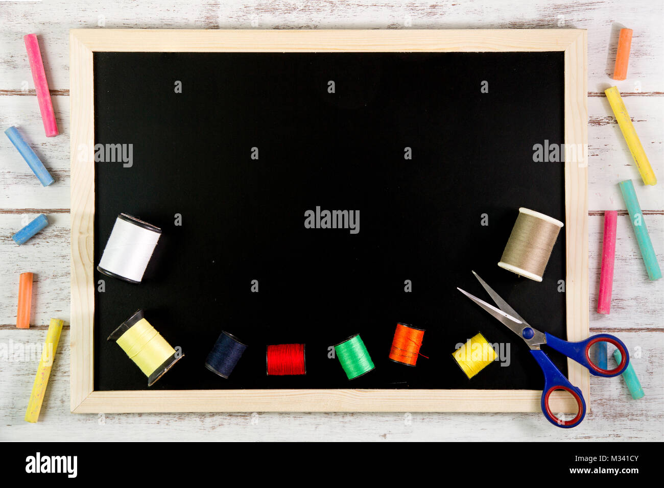 Blank blackboard and sewing threads on wooden table.Template mock up ...
