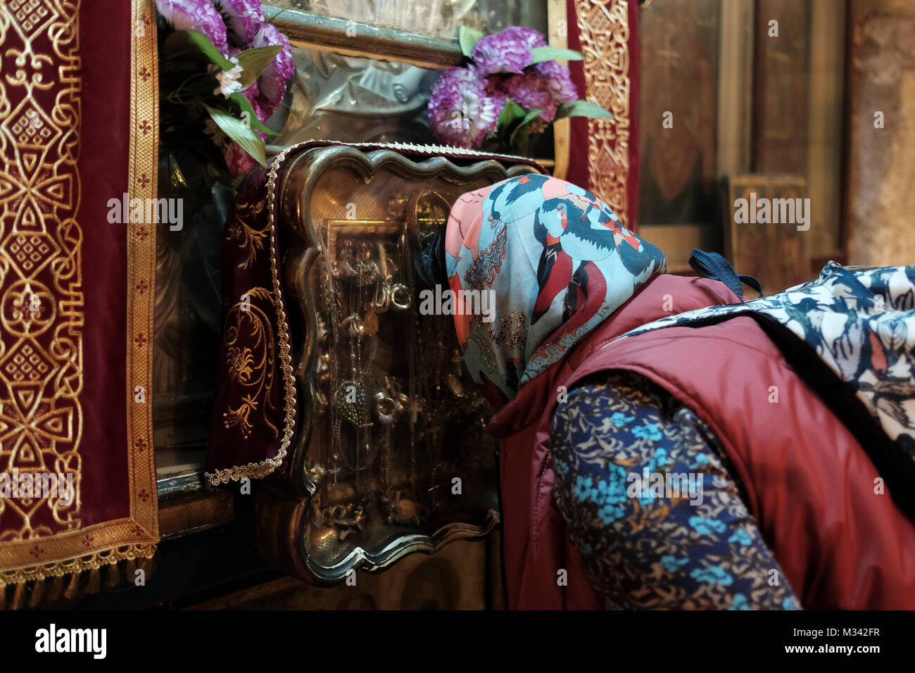 An Eastern Orthodox Christian worshiper kissing a religious icon inside ...