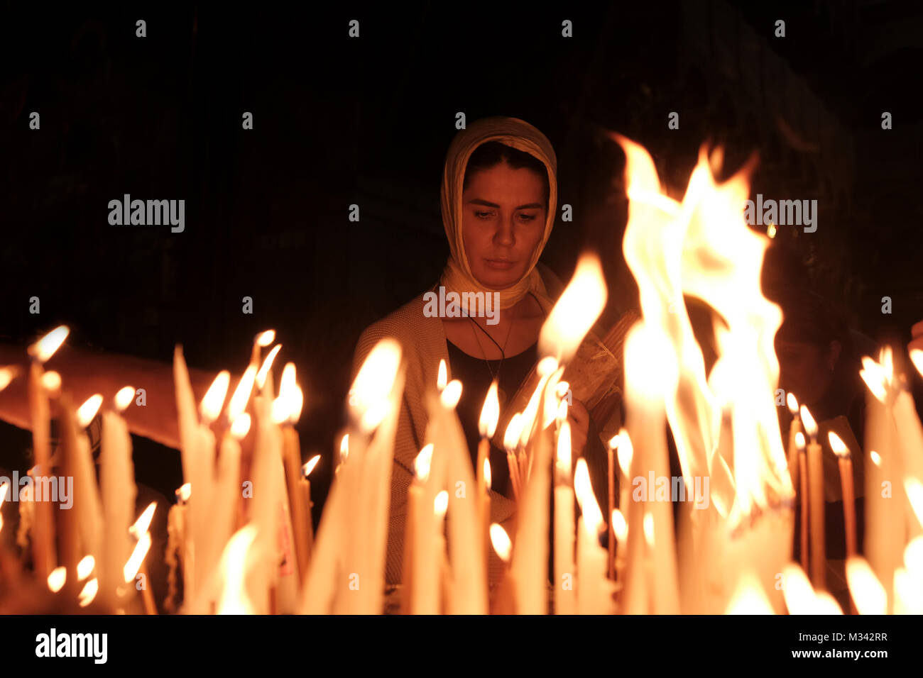An Orthodox Christian pilgrim lights candles as she prays inside the ...